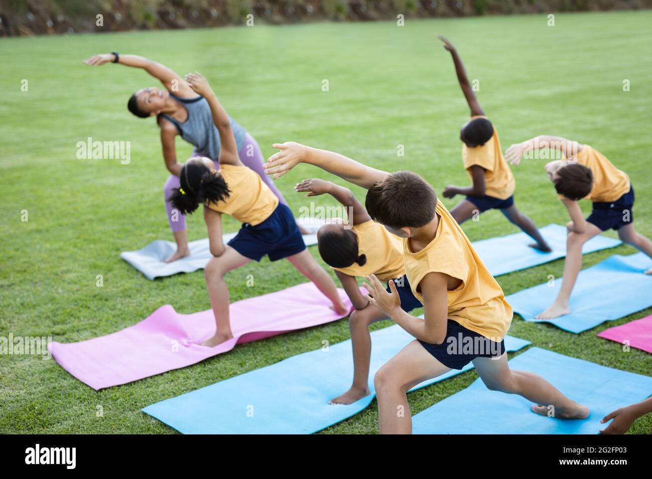 Female teacher and group of diverse students performing stretching ...