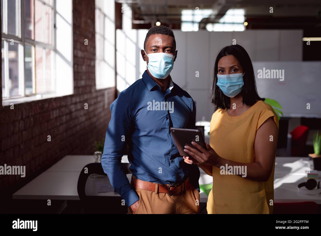 Portrait of diverse male and female colleague wearing face masks ...