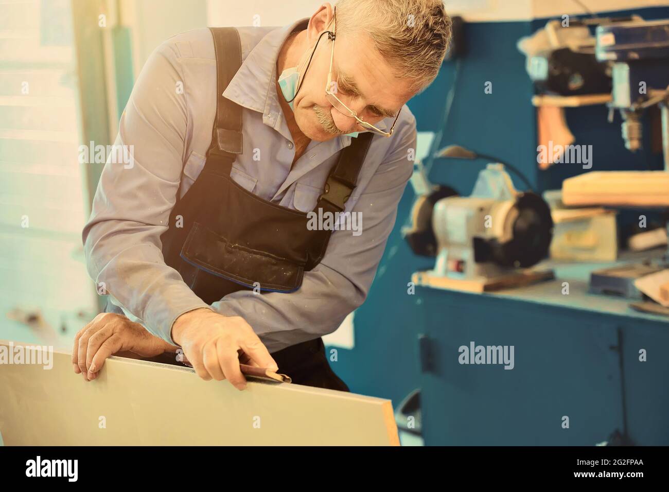 Portrait of an elderly carpenter or carpenter in overalls working with ...