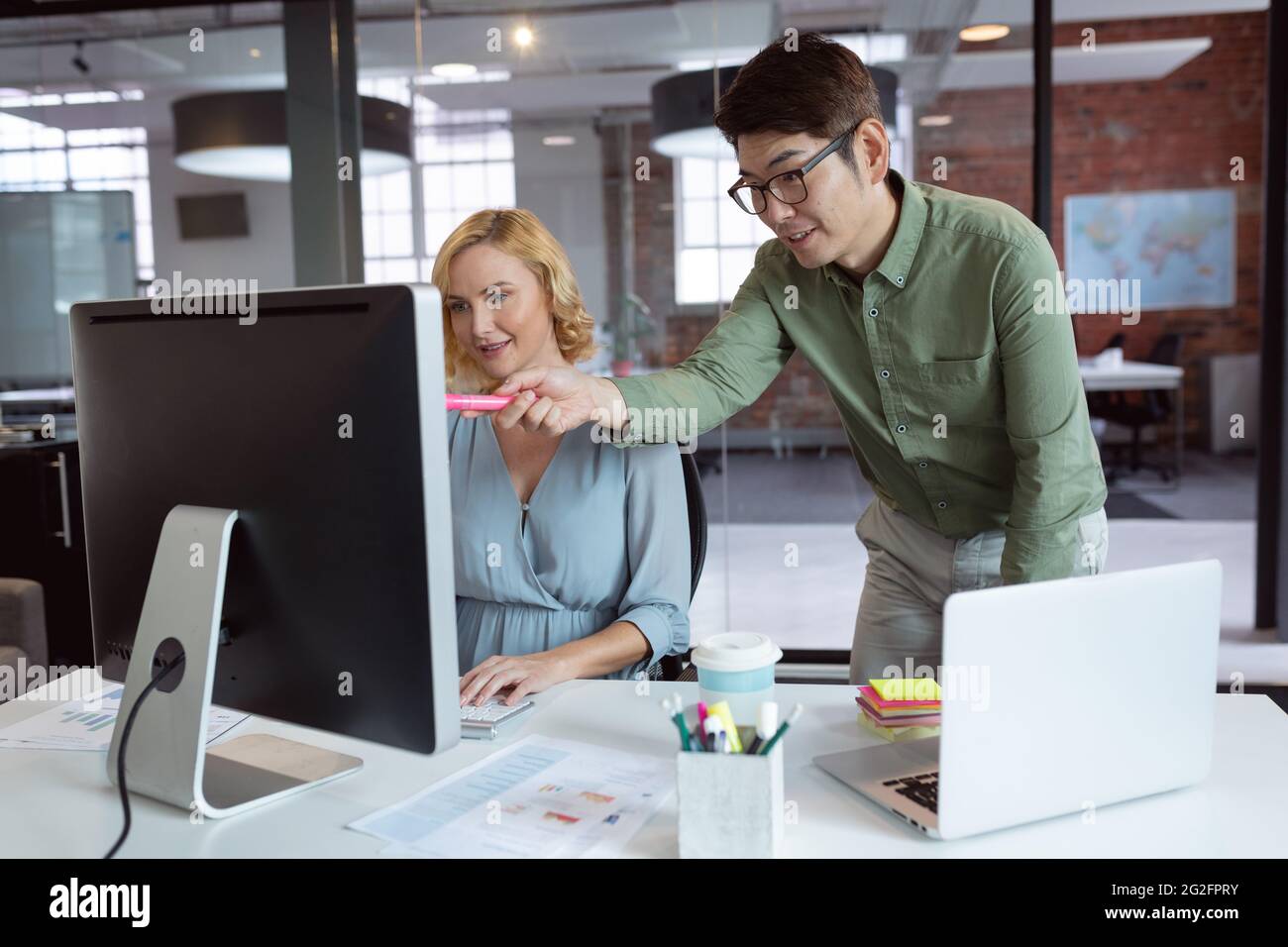 Happy diverse male and female colleague looking at computer screen and ...