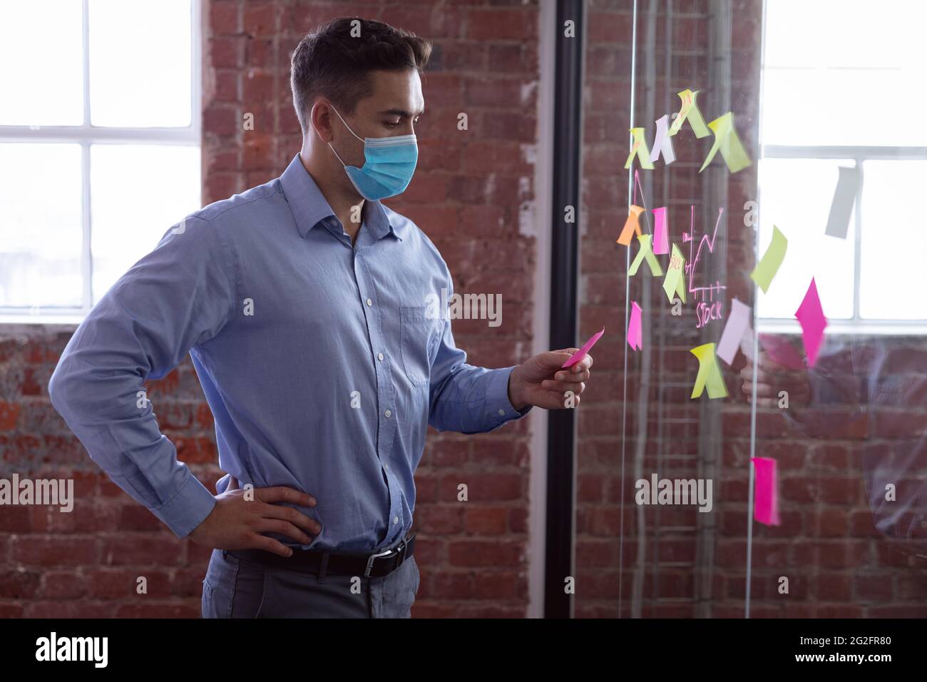 Caucasian businessman wearing face mask brainstorming, reading memo ...