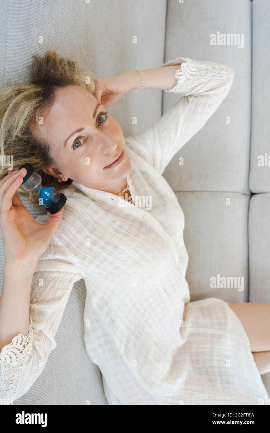Lying young woman with sand clock on her hand. Portrait of woman on ...