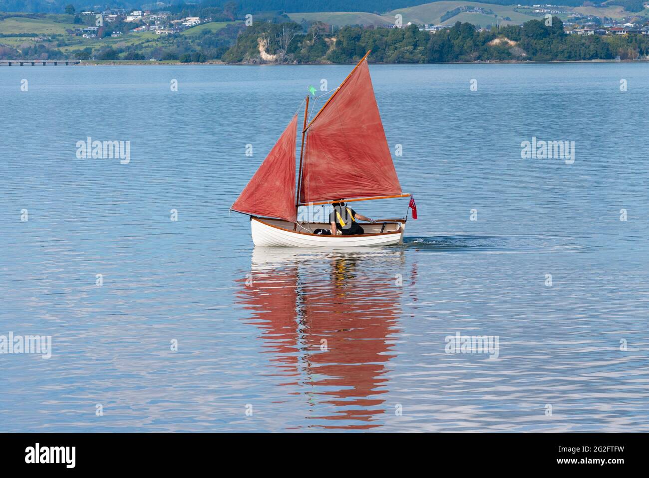 Traditional style red sails on small yacht becalmed in bay Stock Photo ...