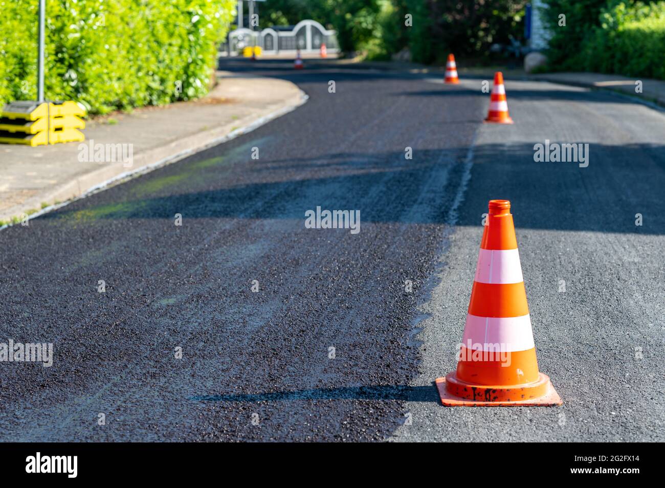 Construction cones marking part of road with a layer of fresh asphalt ...