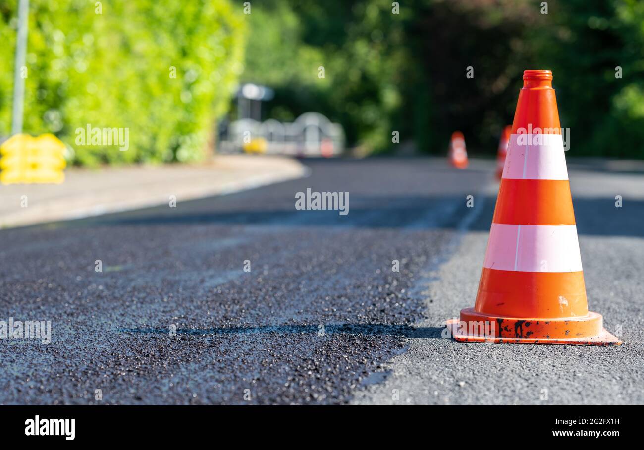 Construction cones marking part of road with a layer of fresh asphalt ...