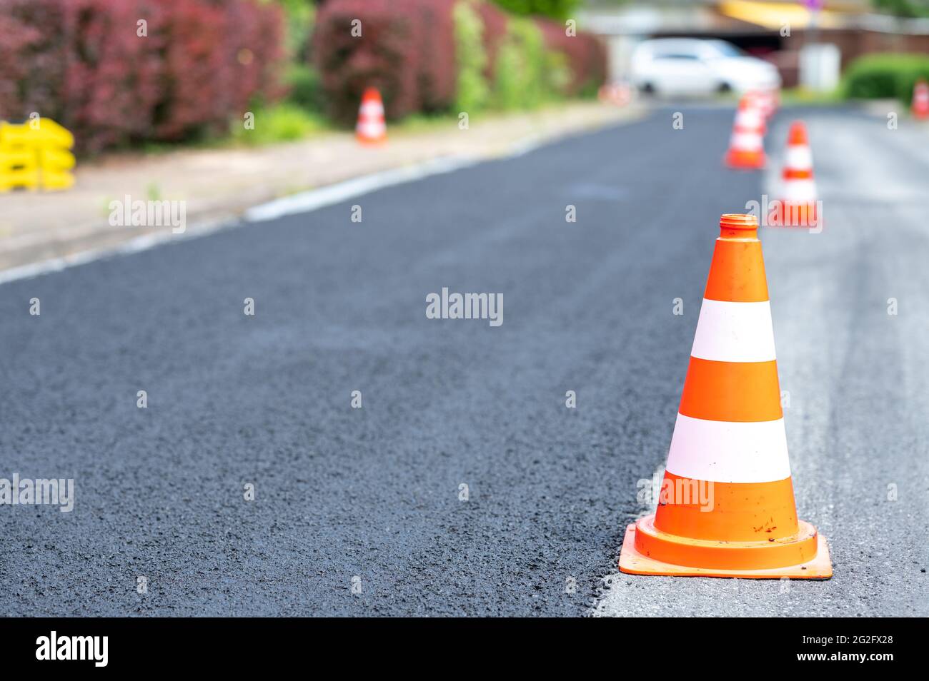 Construction cones marking part of road with a layer of fresh asphalt ...