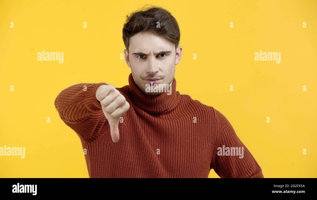 Skeptical man in sweater showing dislike isolated on yellow Stock Photo ...