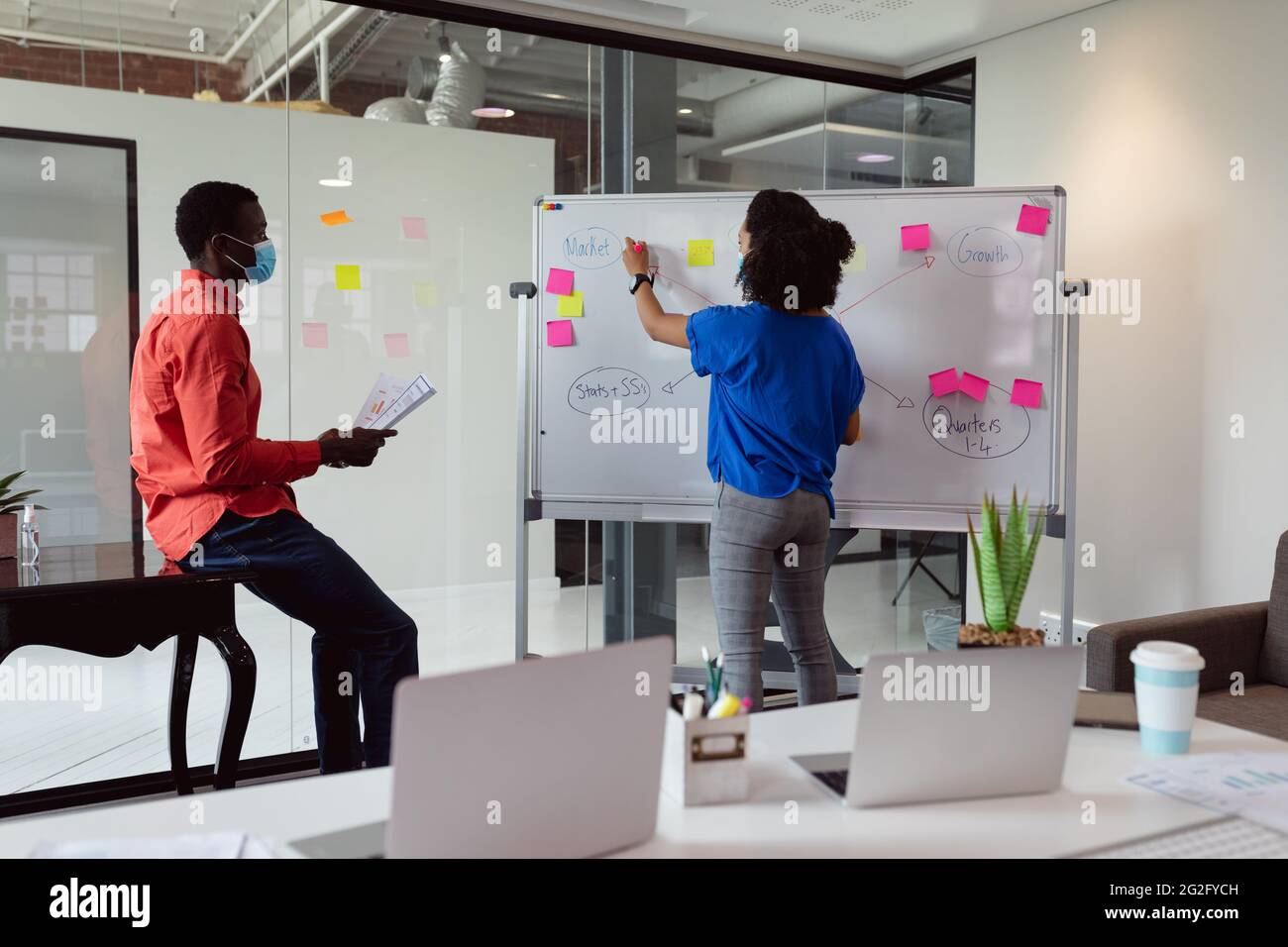 Diverse male and female colleague in face masks brainstorming at ...
