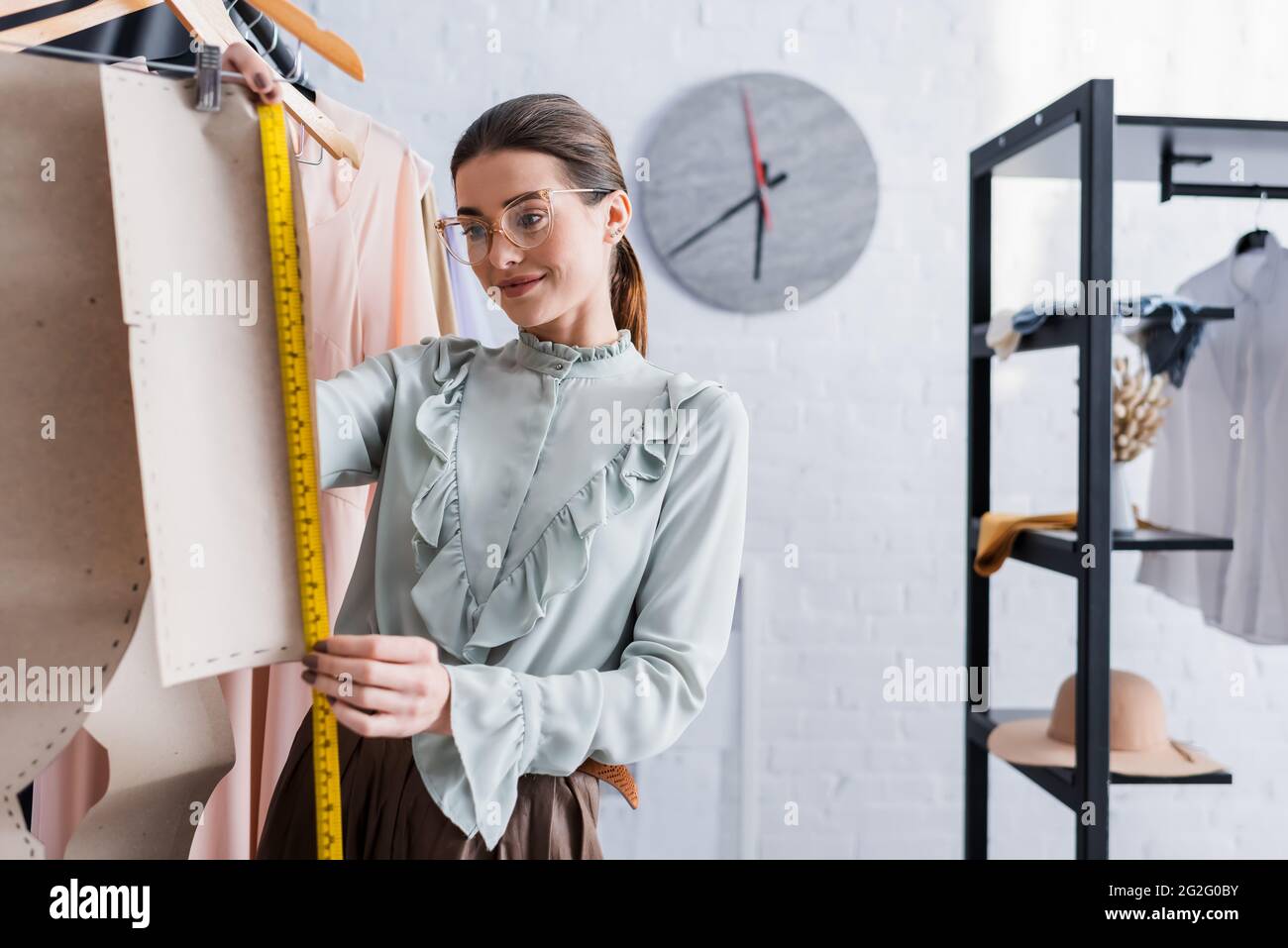 Smiling designer measuring sewing pattern in atelier Stock Photo - Alamy