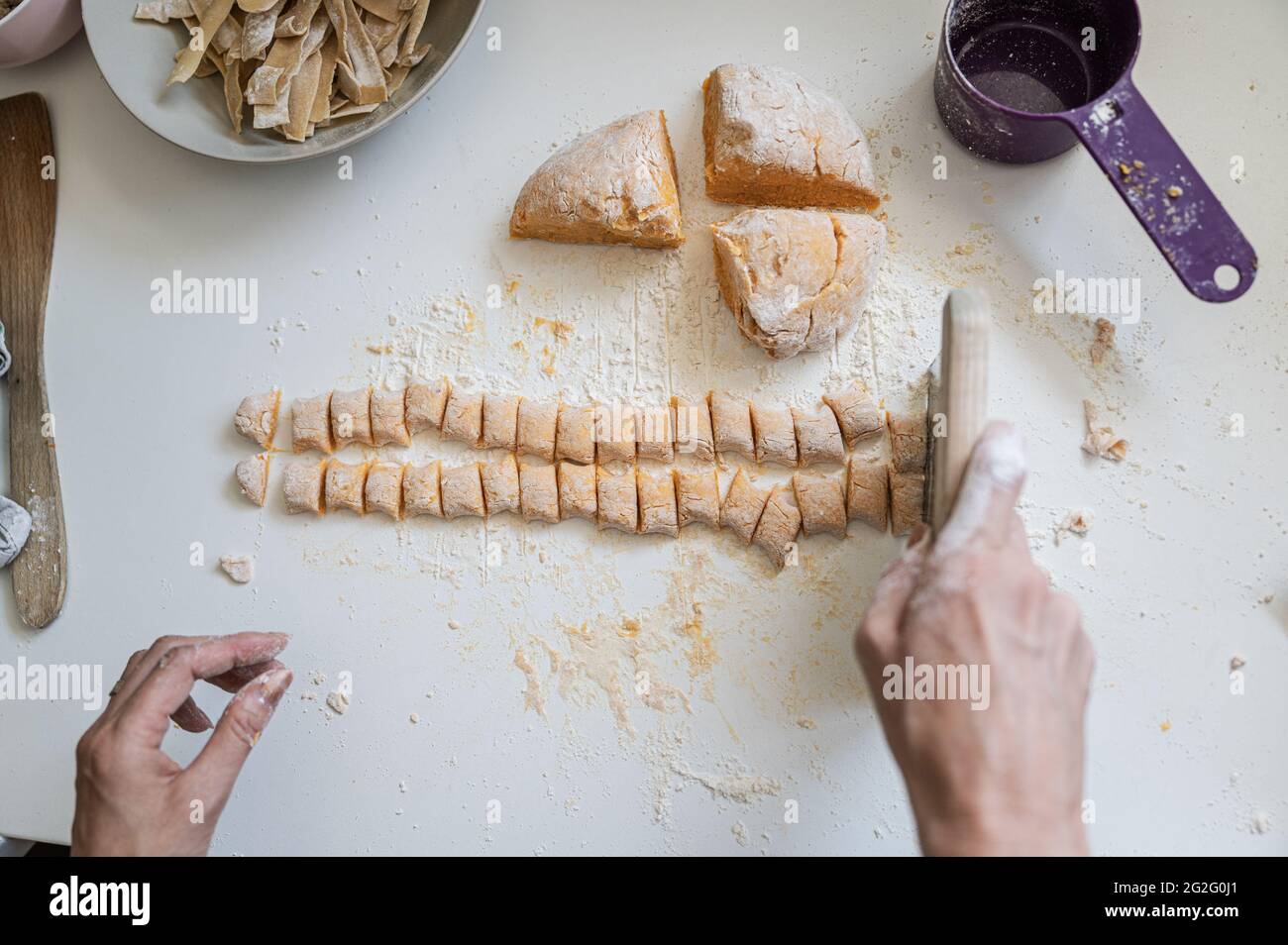 Top view of a woman making homemade vegan sweet potato gnocchi on flour ...