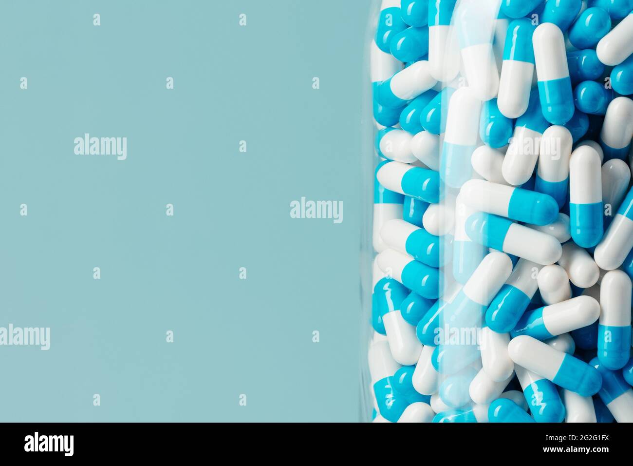 glass dome filled with white and blue pills or tablets on a blue ...