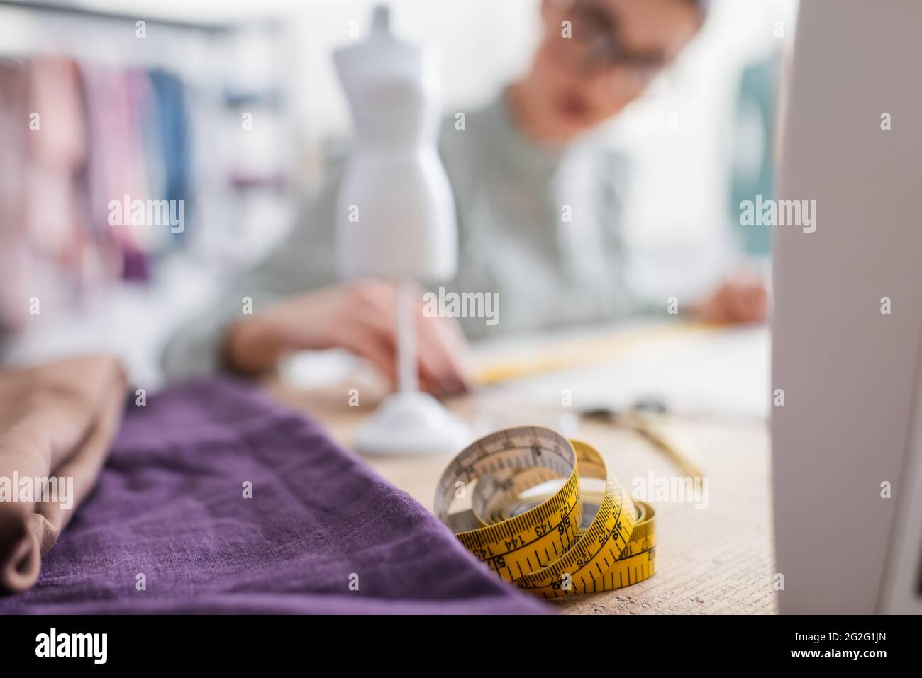 Measuring tape and fabric near blurred seamstress Stock Photo - Alamy