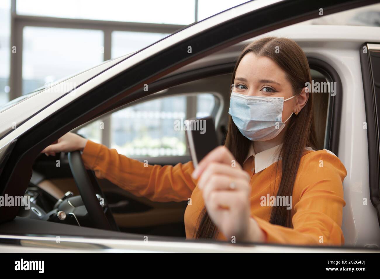 Female driver wearing medical face mask, holding out car key to the ...