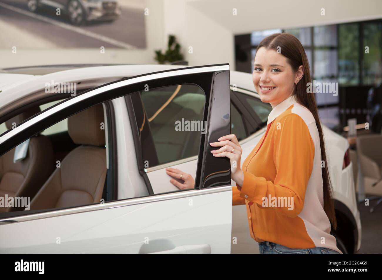 Gorgeous happy young woman buying new car at the dealership, copy space ...