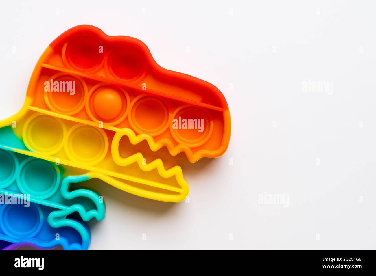 Popit rainbow toy in rainbow colours and dino shape. Trendy bubble pop ...