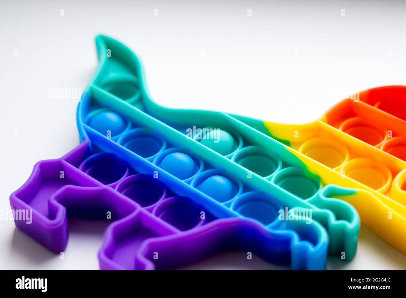 Popit rainbow toy in rainbow colours and dino shape. Trendy bubble pop ...