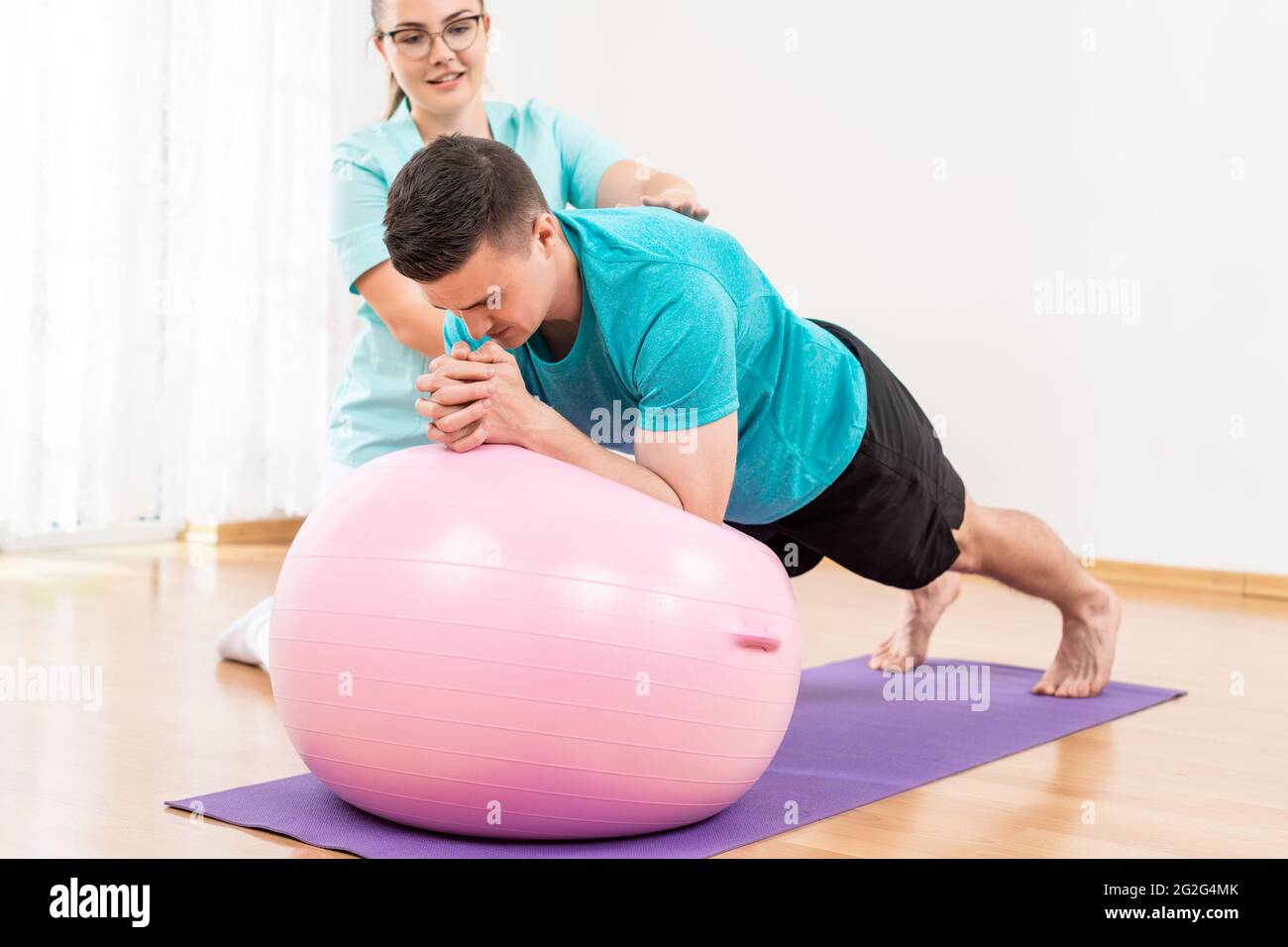 Physiotherapist working with young male client on core strength using ...