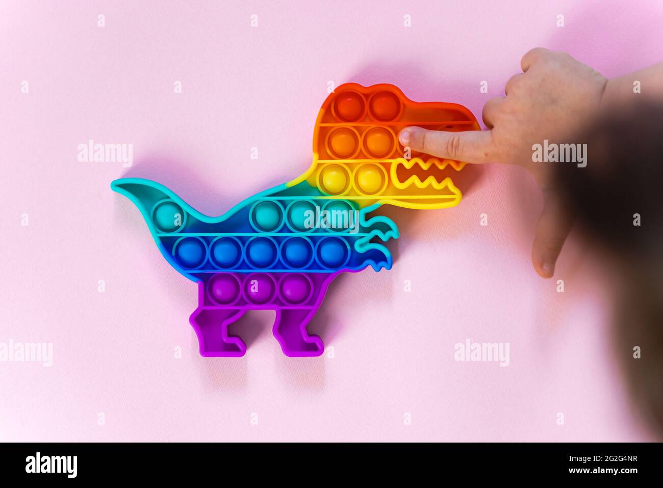 Popit rainbow toy in rainbow colours and dino shape. Trendy bubble pop ...