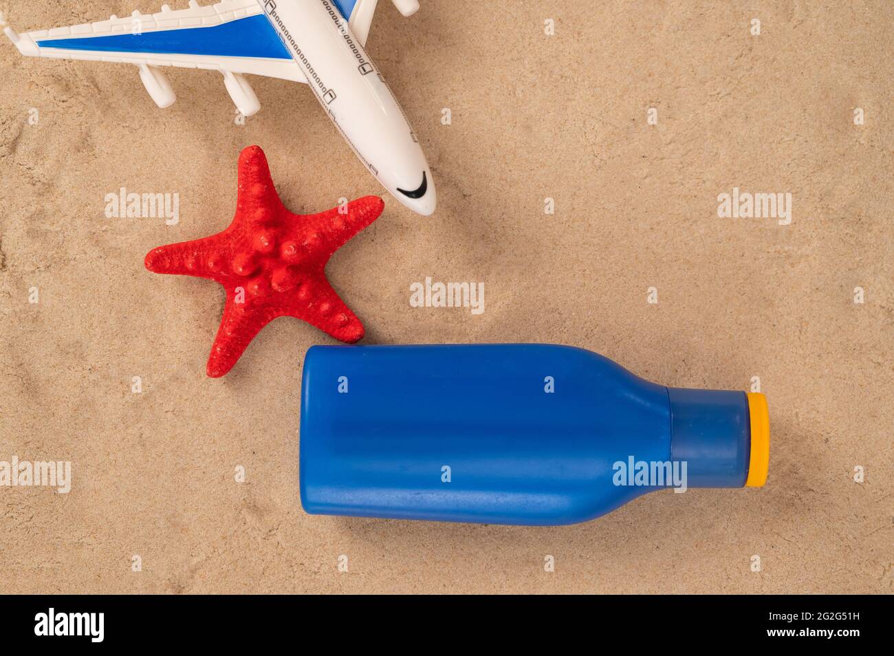 Airplane model red starfish and a tube of sunscreen on the sand ...
