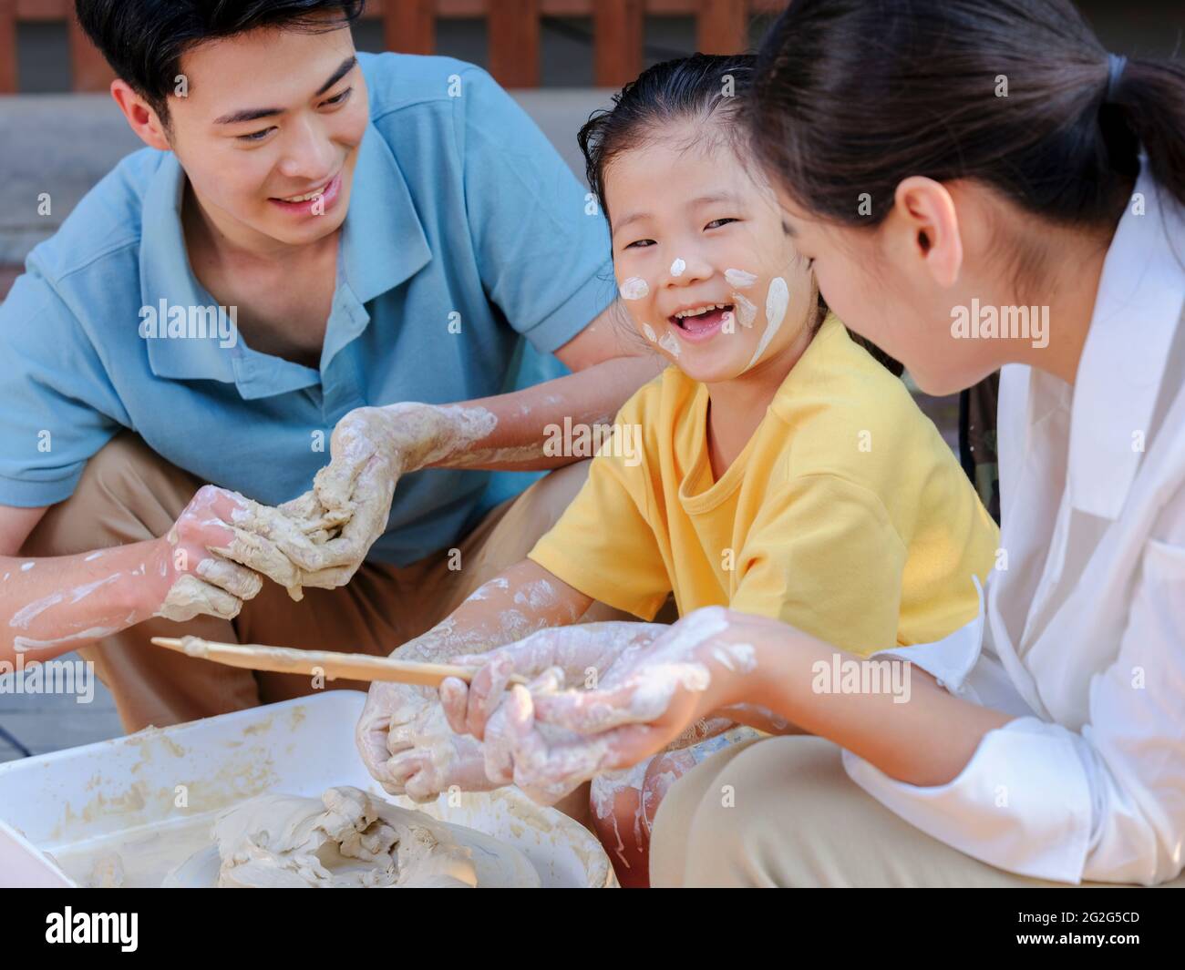 Happy family of three doing pottery together outdoors high quality ...
