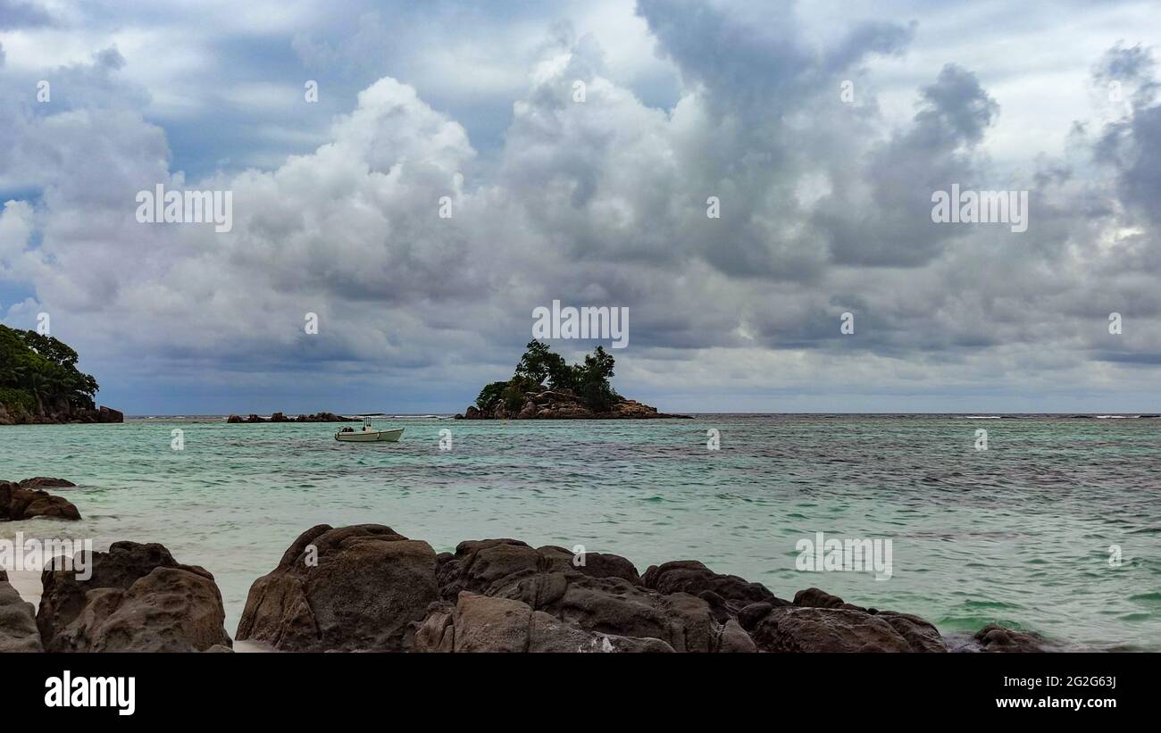Seychelles, Mahe, small boat and rocks in the water. Cloudy sky Stock ...