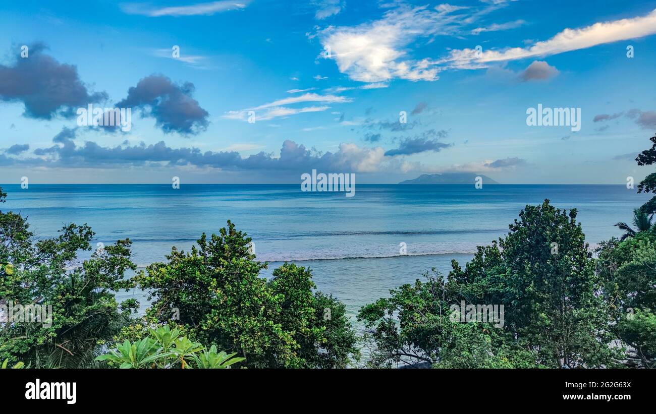 Cloudy blue sky, calm blue Indian Ocean, Seychelles, Mahe, Beau Vallon ...