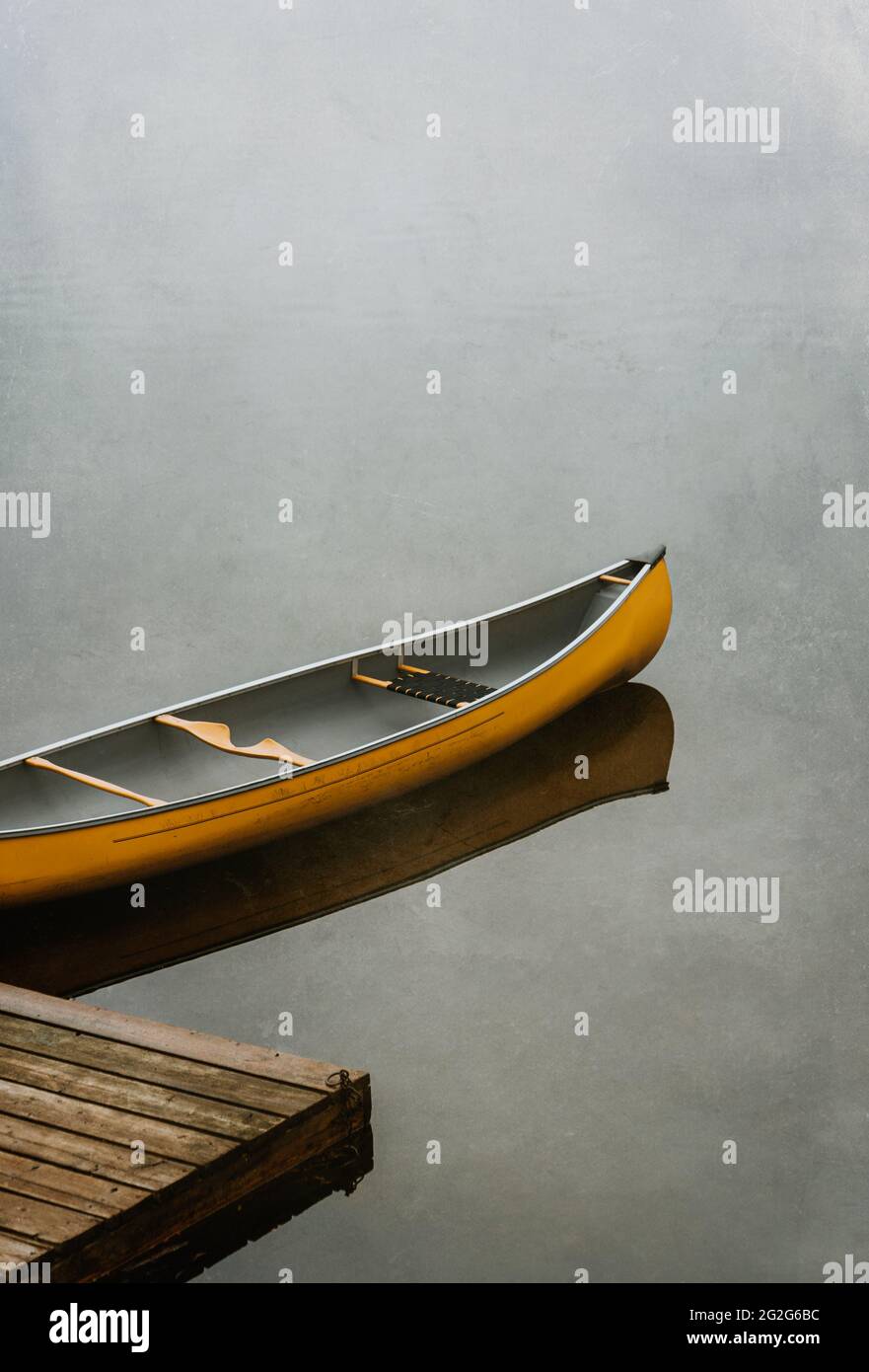 Empty yellow canoe at a wooden dock on a calm lake in Canada Stock ...
