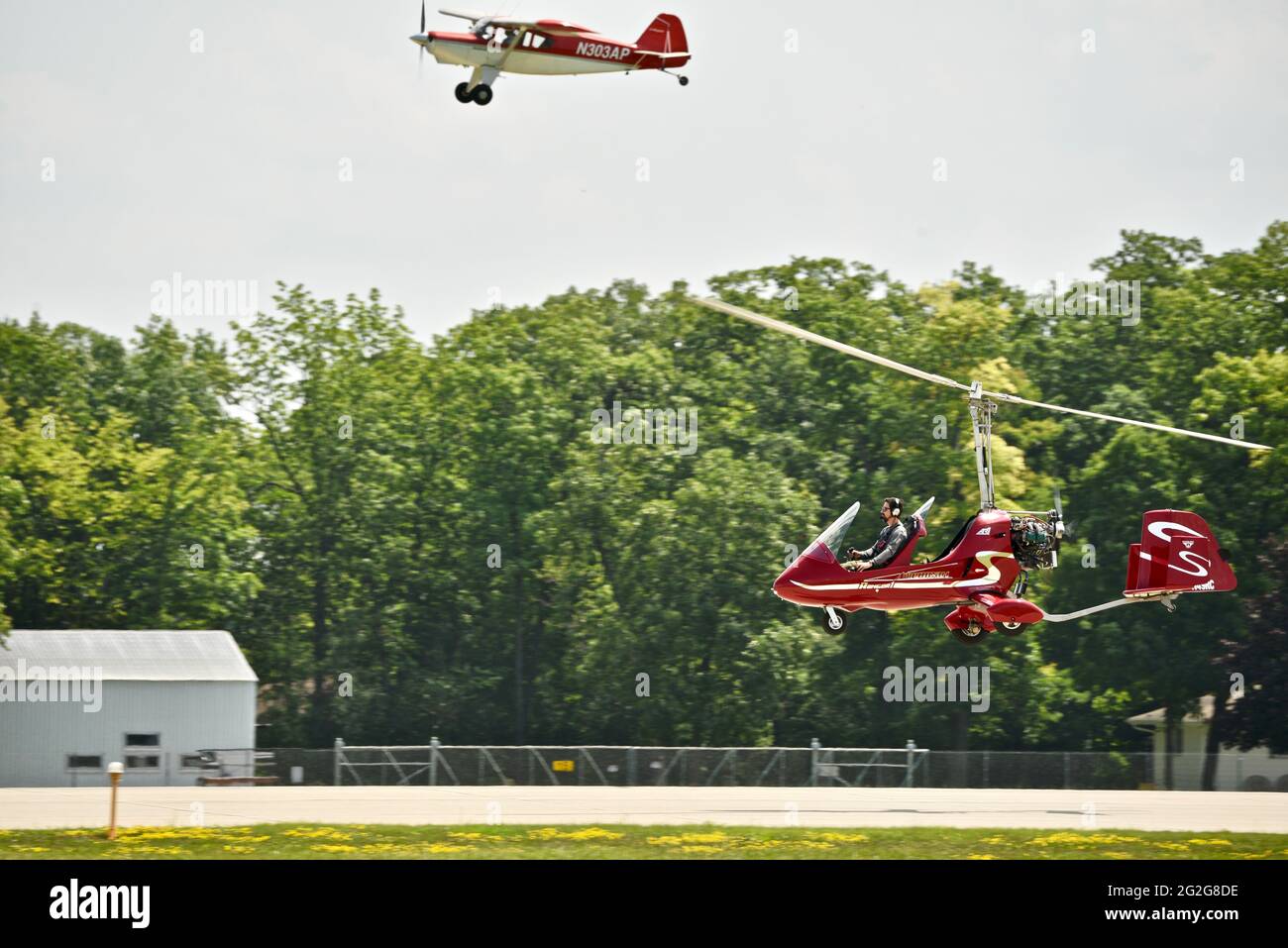 Pilot in open cockpit flying gyroplane, a combination of helicopter and ...