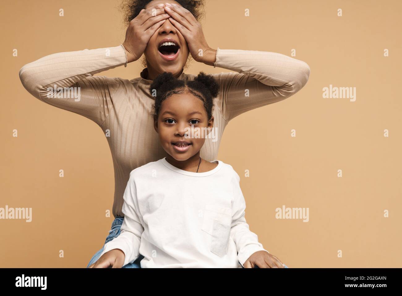 Happy black mother and daughter covering eyes while making fun isolated ...