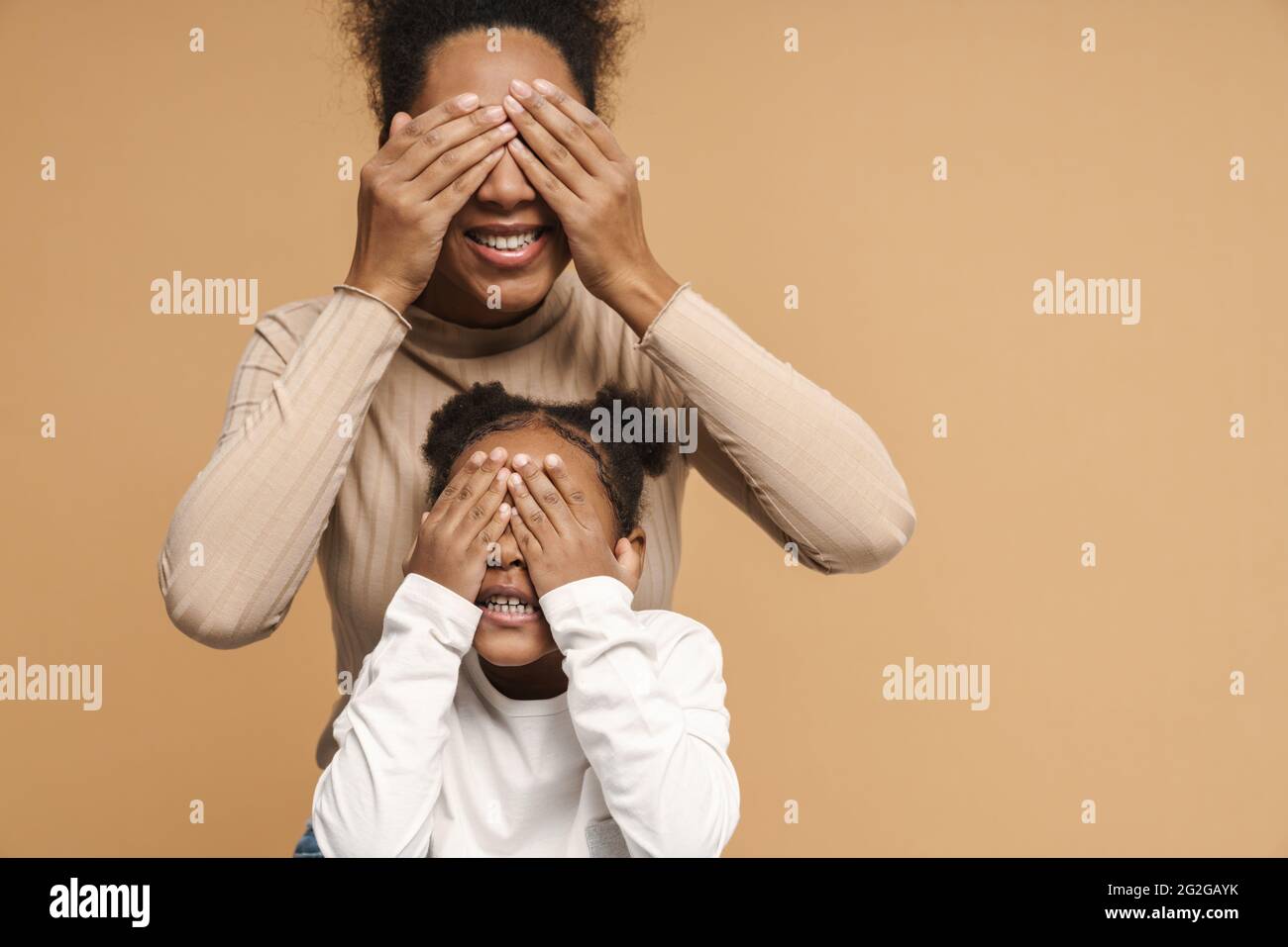 African mother and daughter smiling and covering their eyes isolated ...