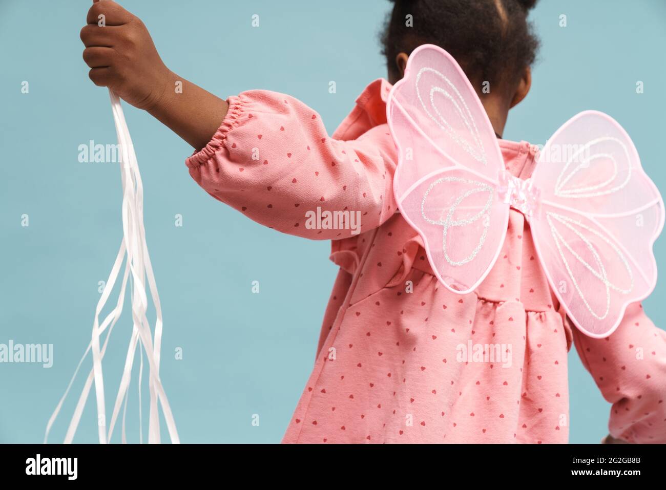 African girl wearing pink dress with angel wings holding ropes isolated ...