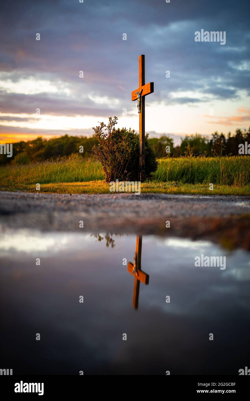 Scenic view of a crucifix on the side of a field with its reflection on ...