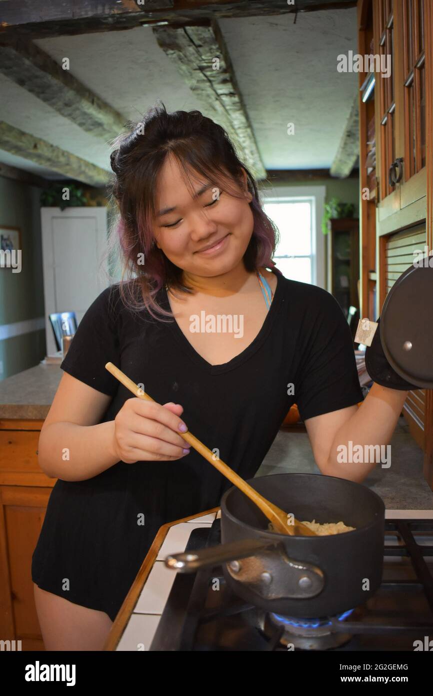 US Asian Woman cooking in kitchen, smiling at food Stock Photo - Alamy