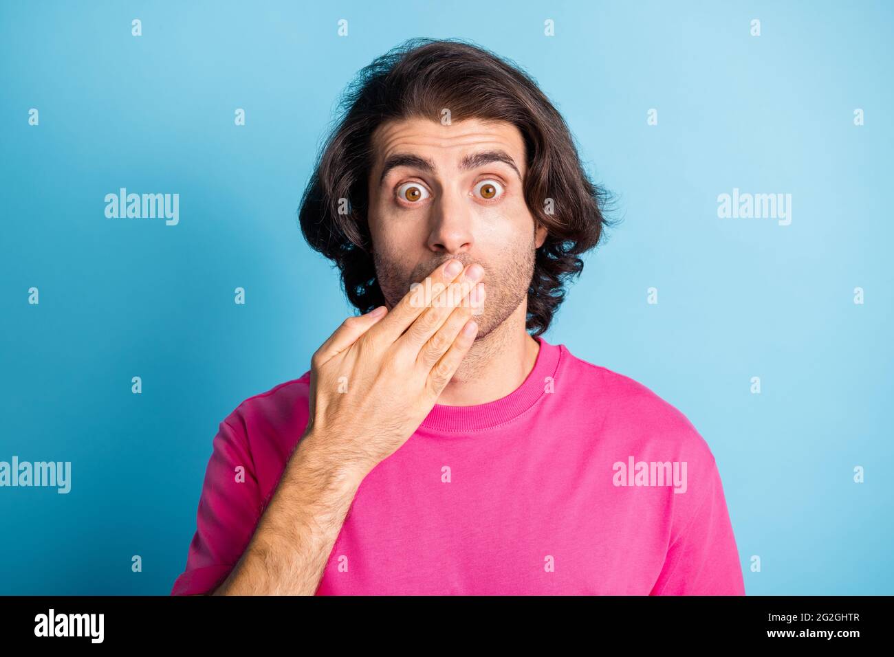 Portrait of amazed sad young man brunet look camera close mouth hands ...