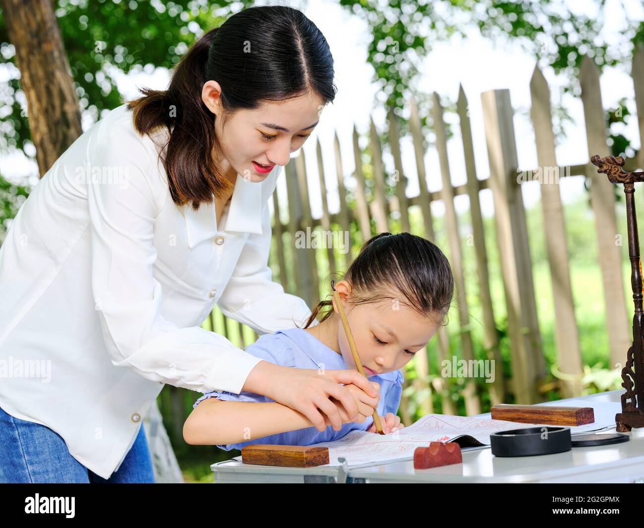 Happy mother and daughter write calligraphy outdoors high quality photo ...