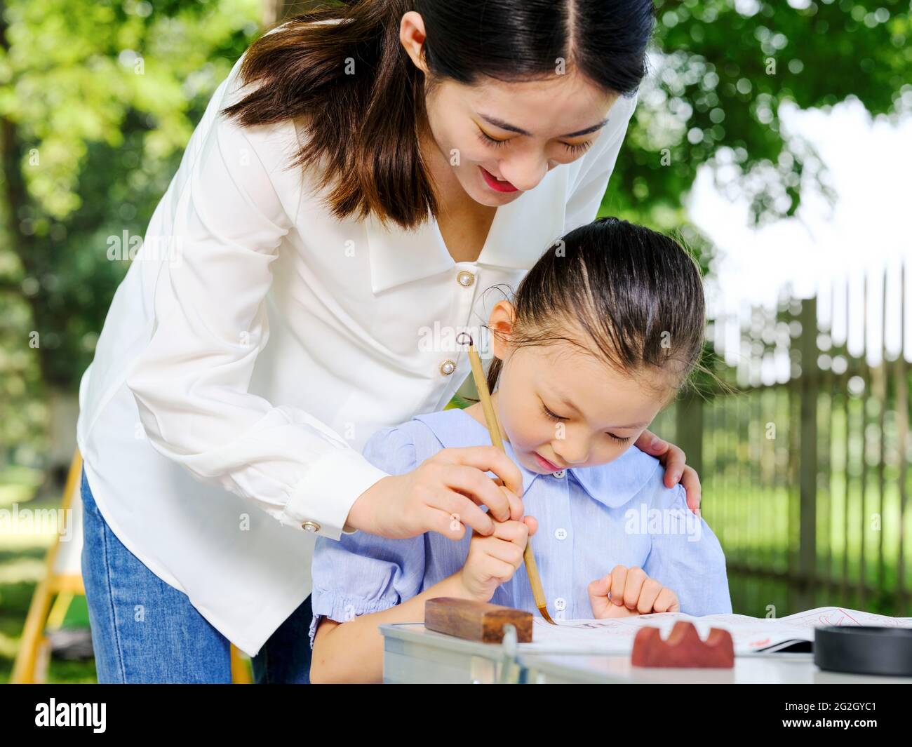 Happy mother and daughter write calligraphy outdoors high quality photo ...