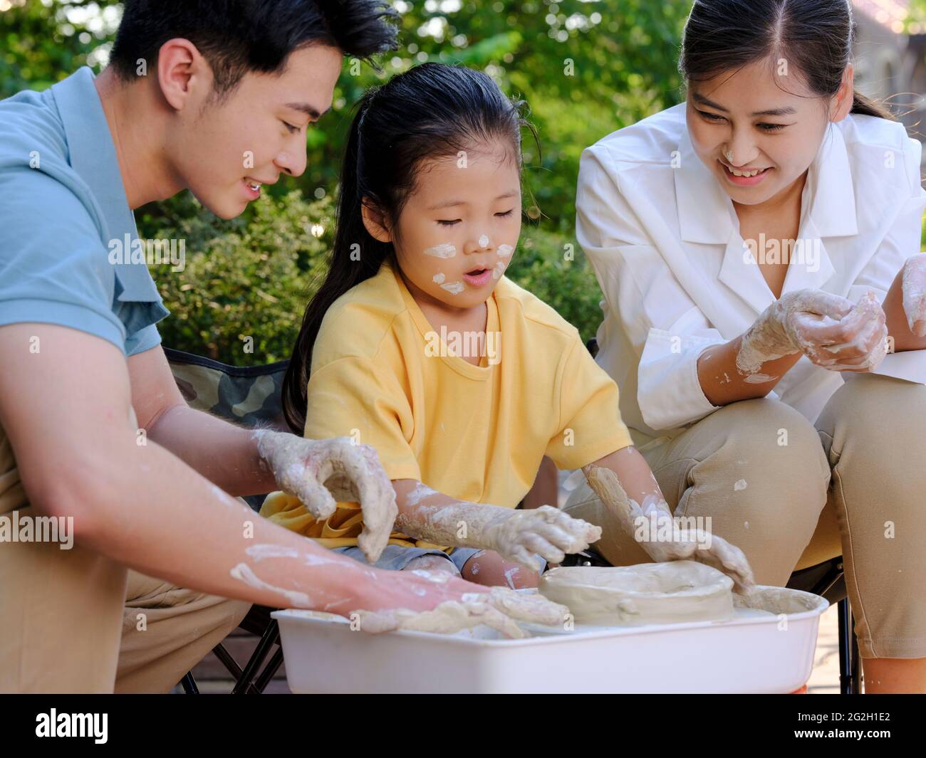 Happy family of three doing pottery together outdoors high quality ...