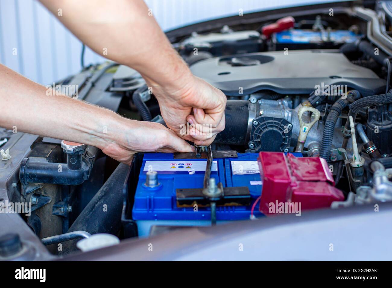 repair and installation of the battery under the hood of a car, a man ...