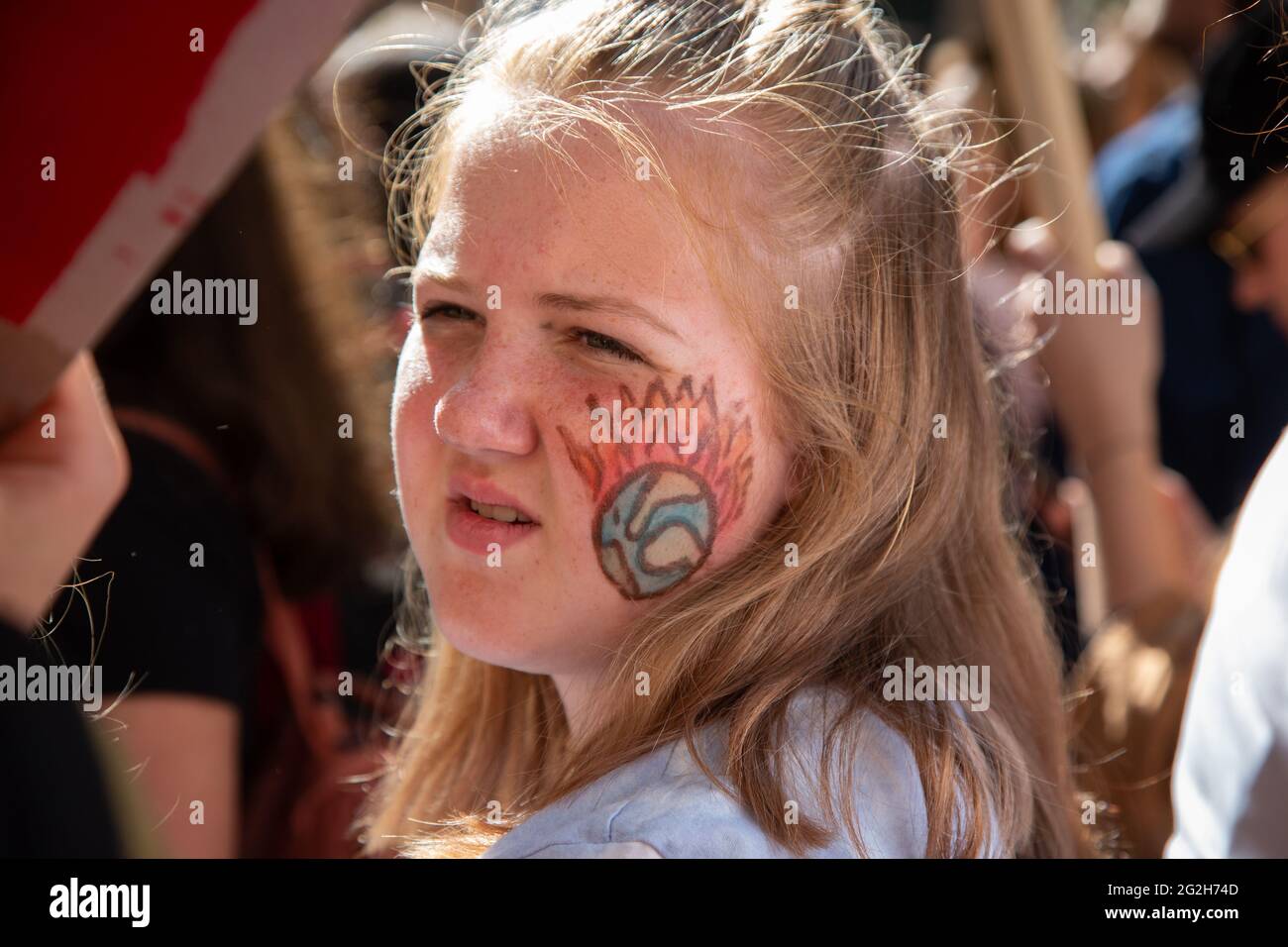 A young girl wearing face paints to protest against global warming at ...