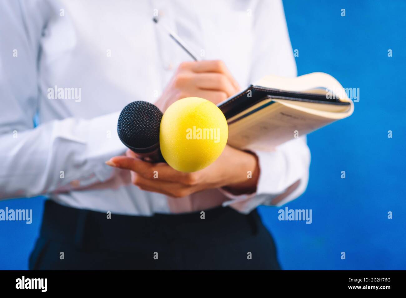 Female reporter with a notebook, a pen, and two microphones taking ...
