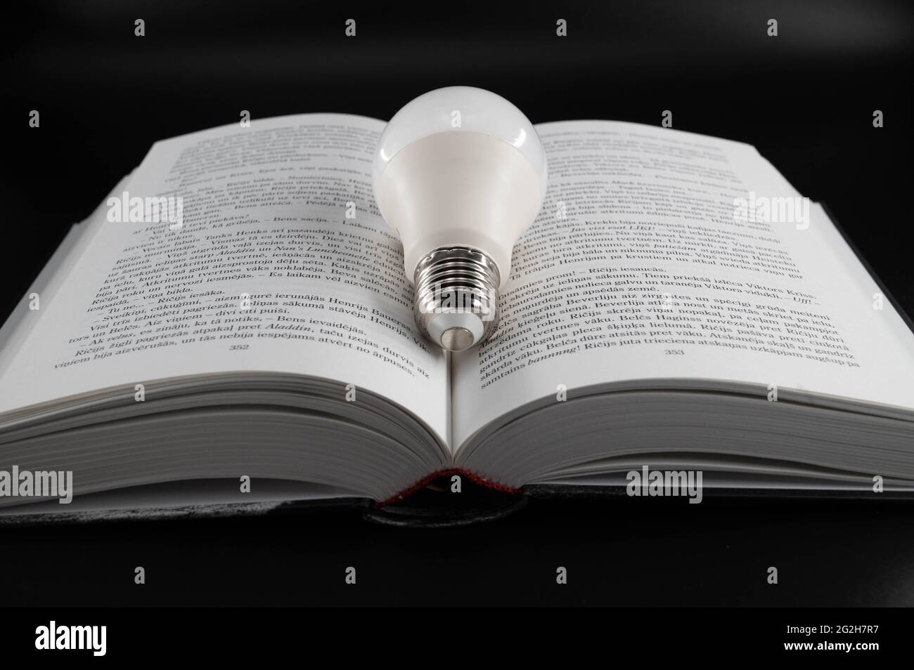 Led bulb in the middle of an open book on an isolated black background ...