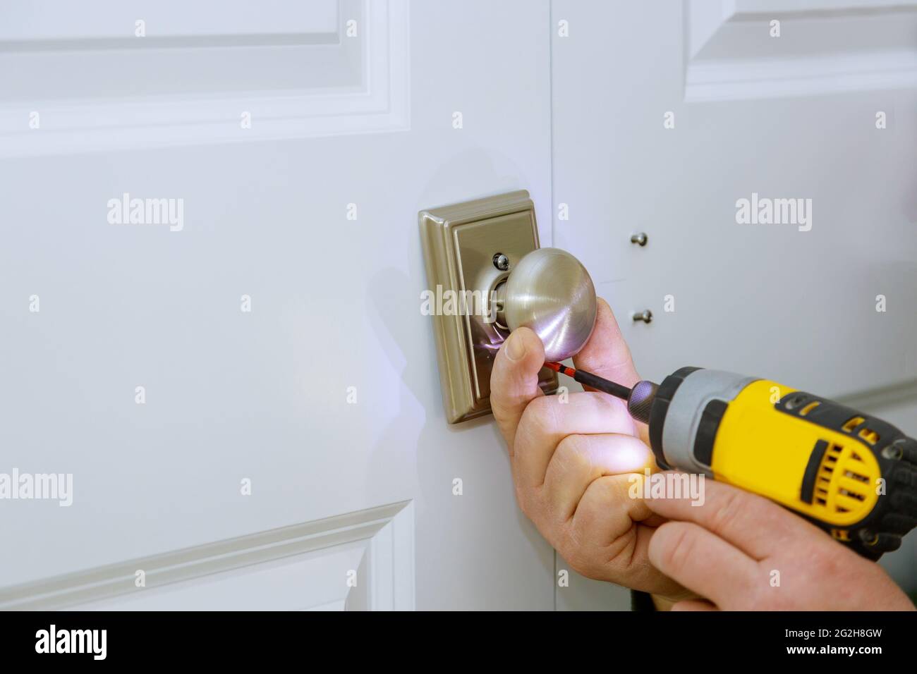 The man is installing the dummy lock of the door by the screwdriver ...