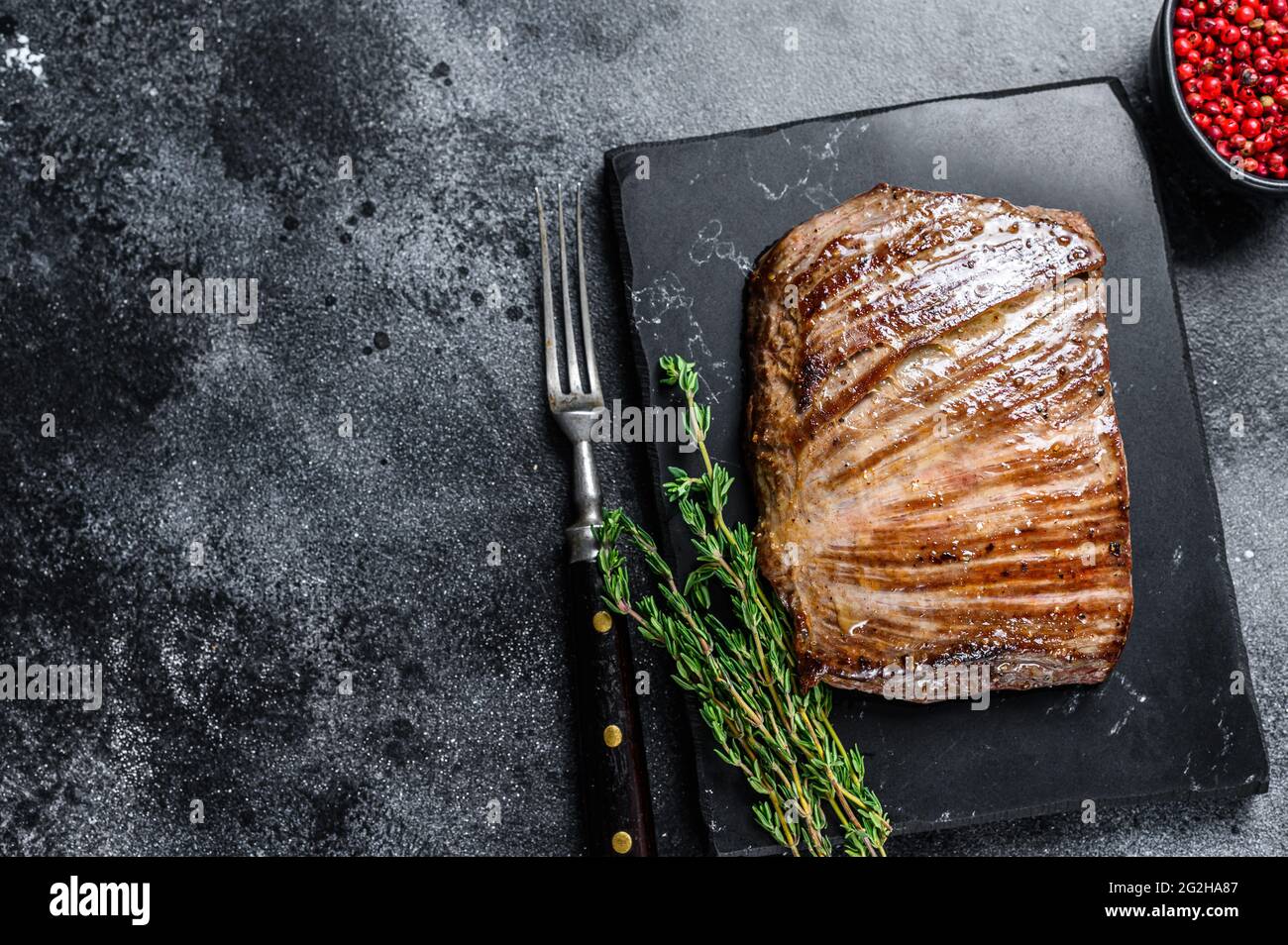 Grilled flank beef meat steak on a marble board. Black background. Top ...