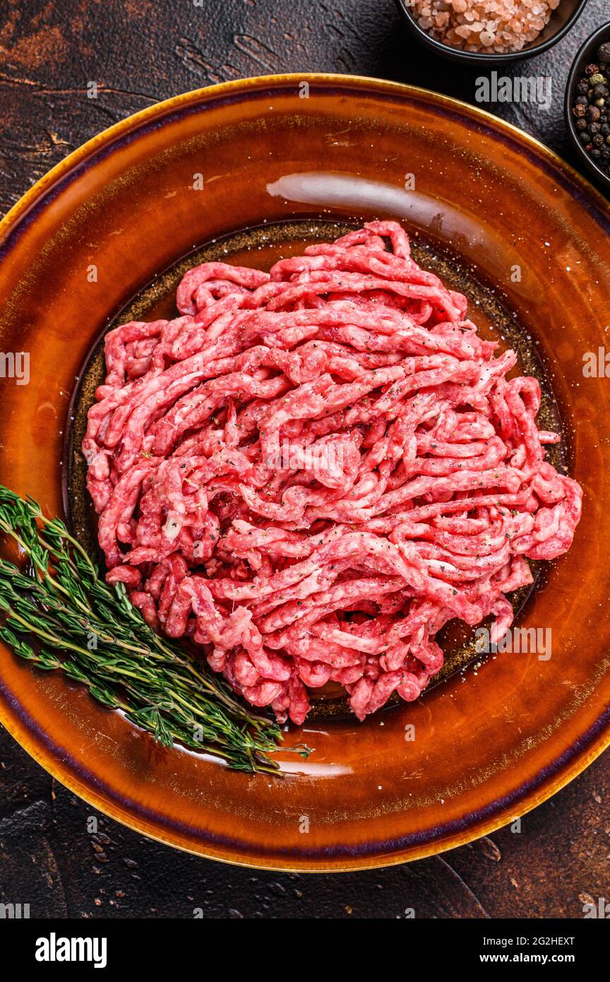 Raw mince angus wagyu beef, ground meat with herbs on a plate. Dark ...