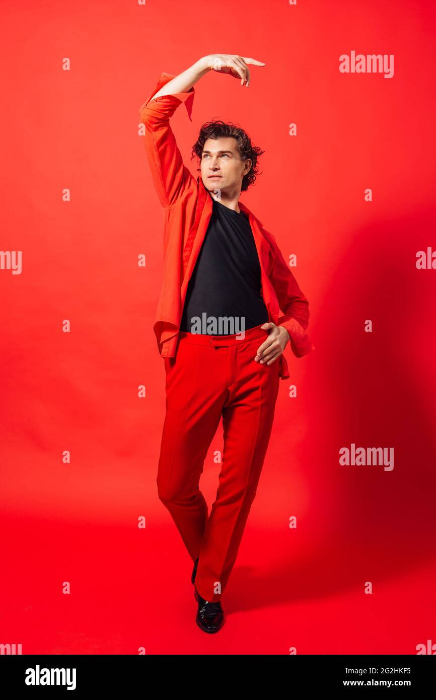 Portrait of a tall handsome man dressed in red shirt posing on the red ...
