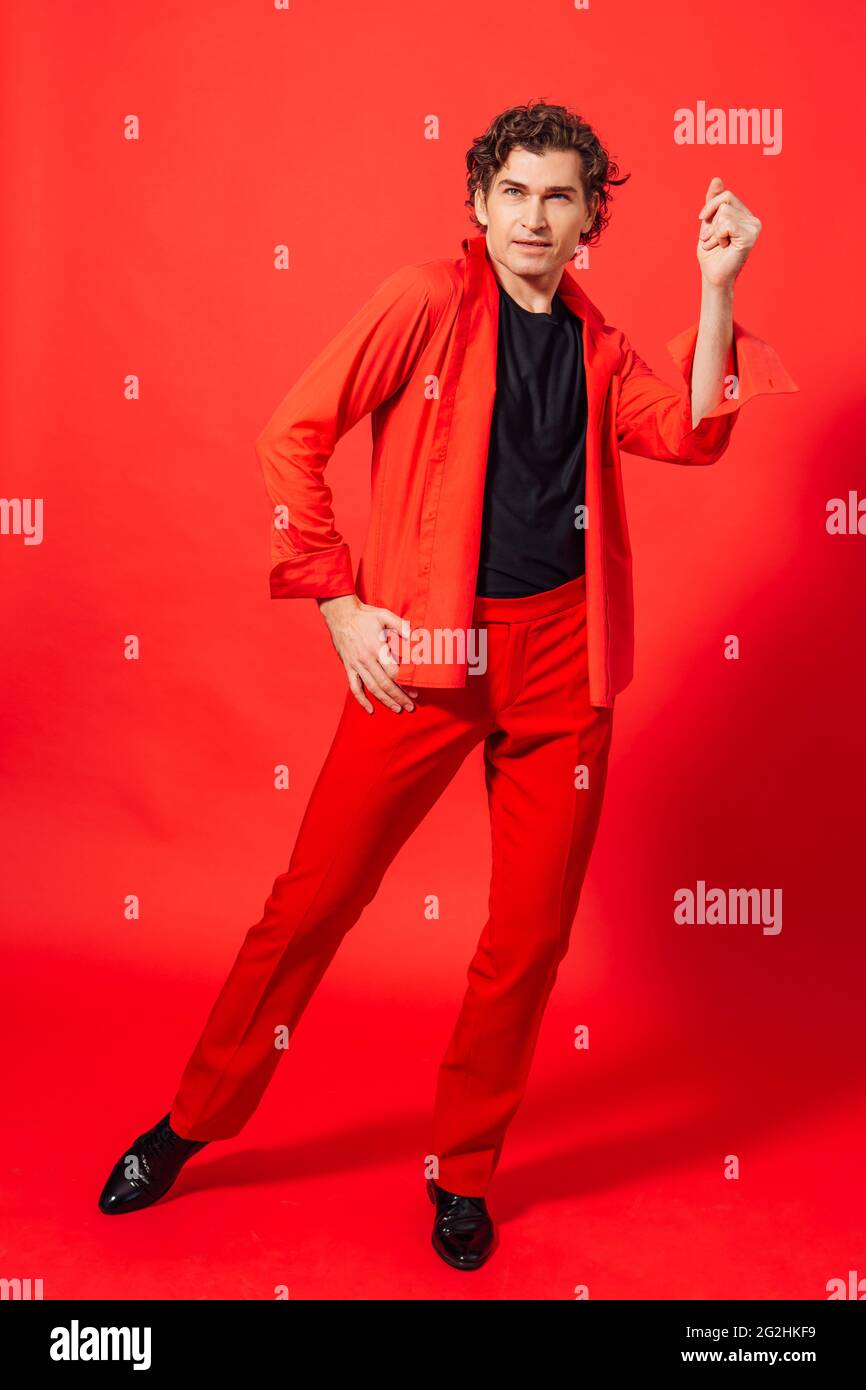 Portrait of a tall handsome man dressed in red shirt posing on the red ...
