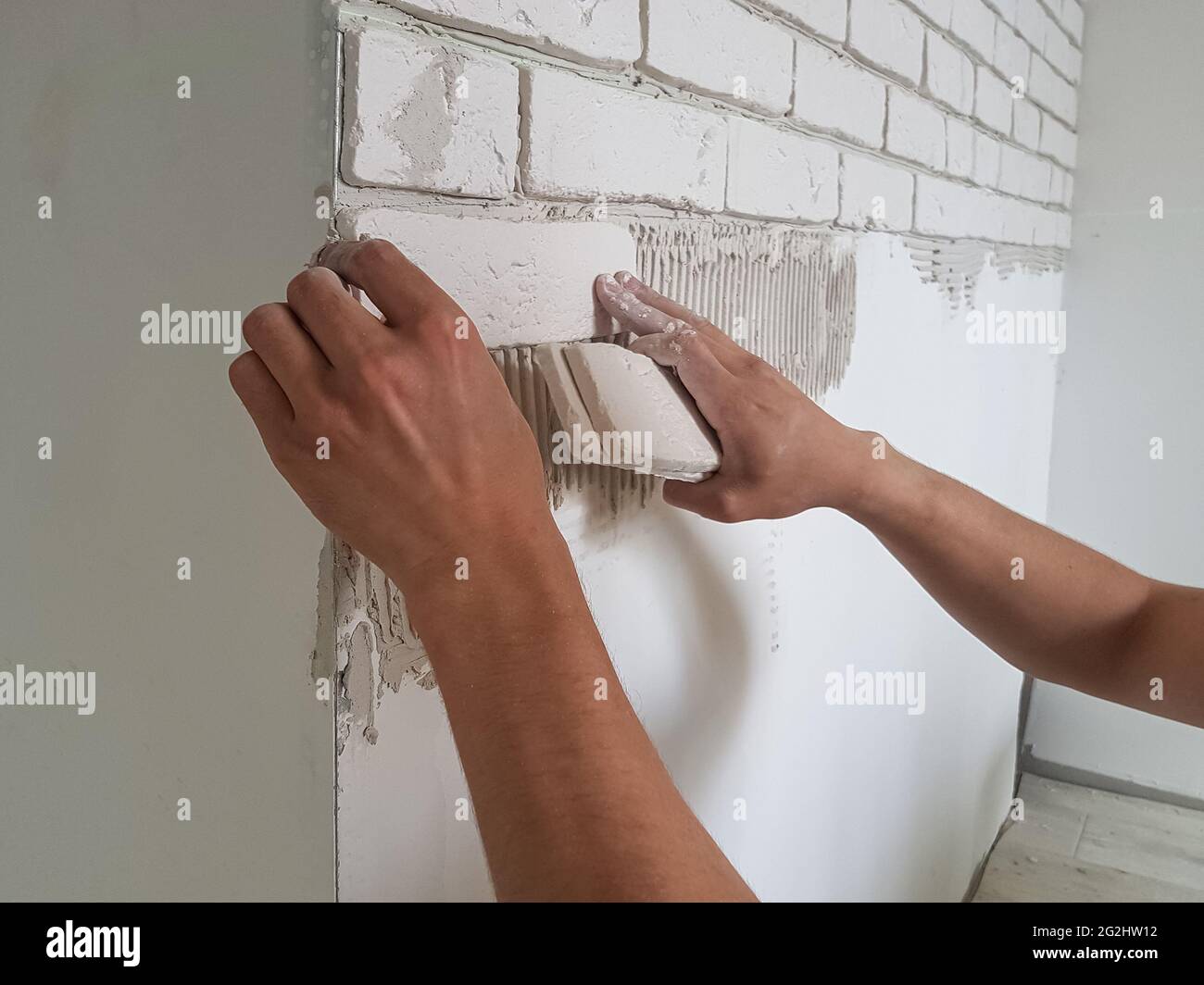 Laying gypsum tiles in rows on the wall with male hands. Home repair ...