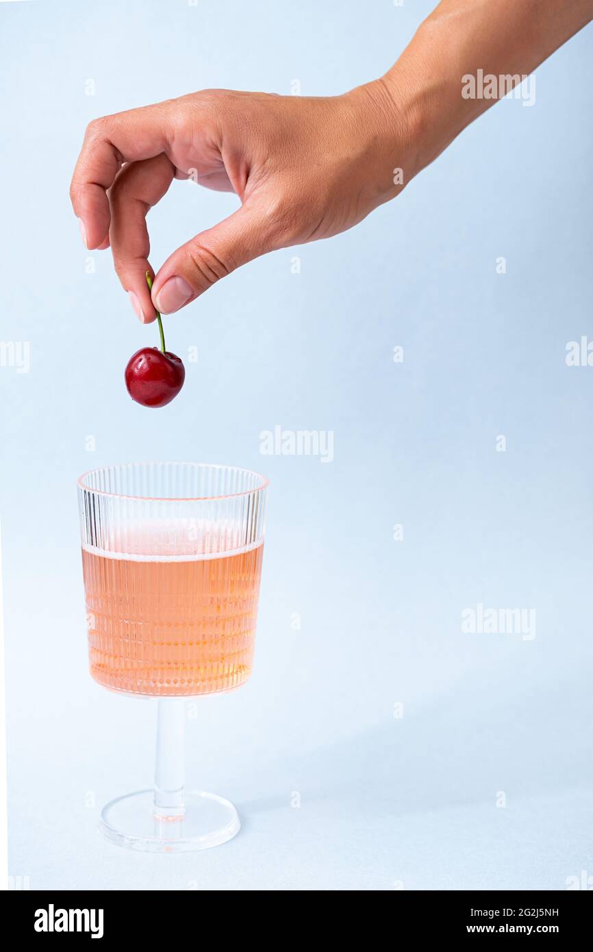 Female hand touch a glass of pink lemonade. Summer drink concept ...