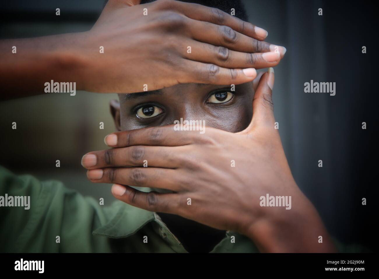 Portrait of young black skin man with hands cover his face standing ...