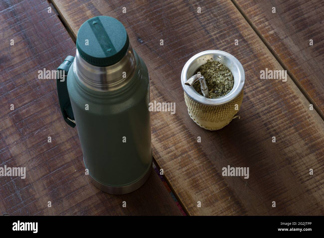 Mate caffeine-rich infused drink in a wood cup next to a thermos bottle ...